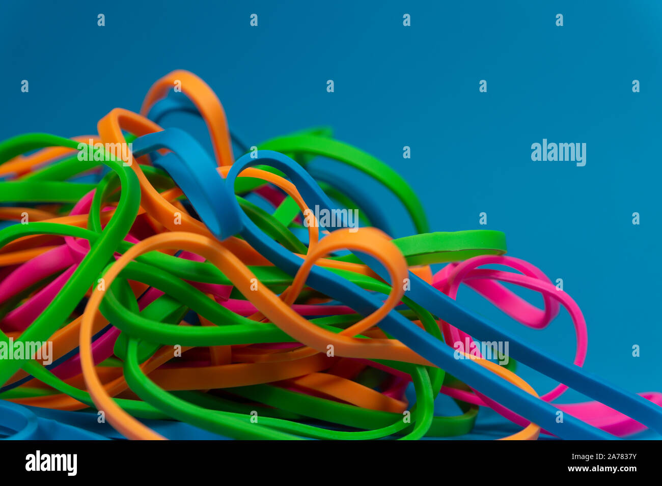Pile of colorful rubber bands over blue background with free space for ...