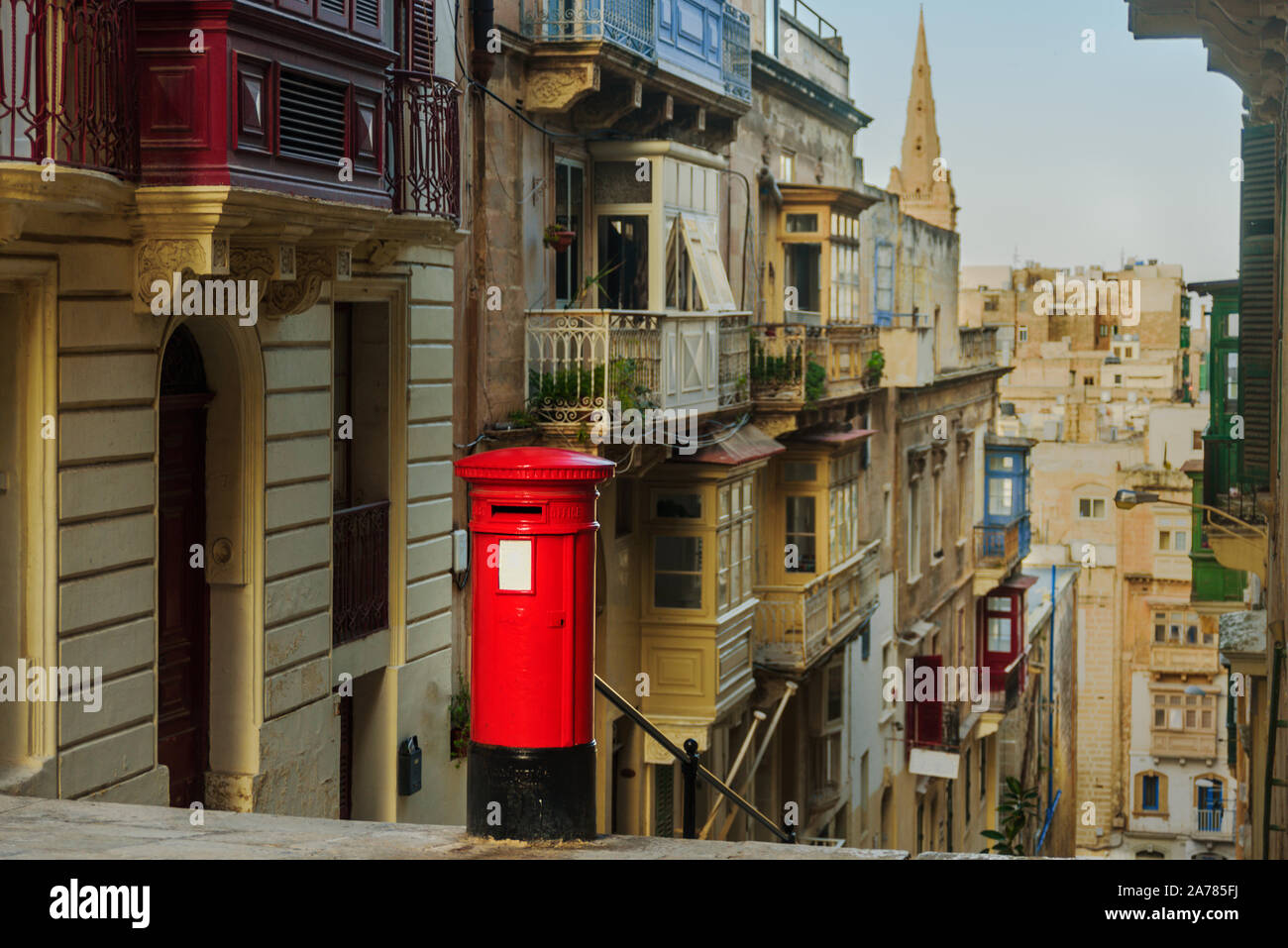 Red traditional postbox in Valletta, Malta. With old balconies on ...