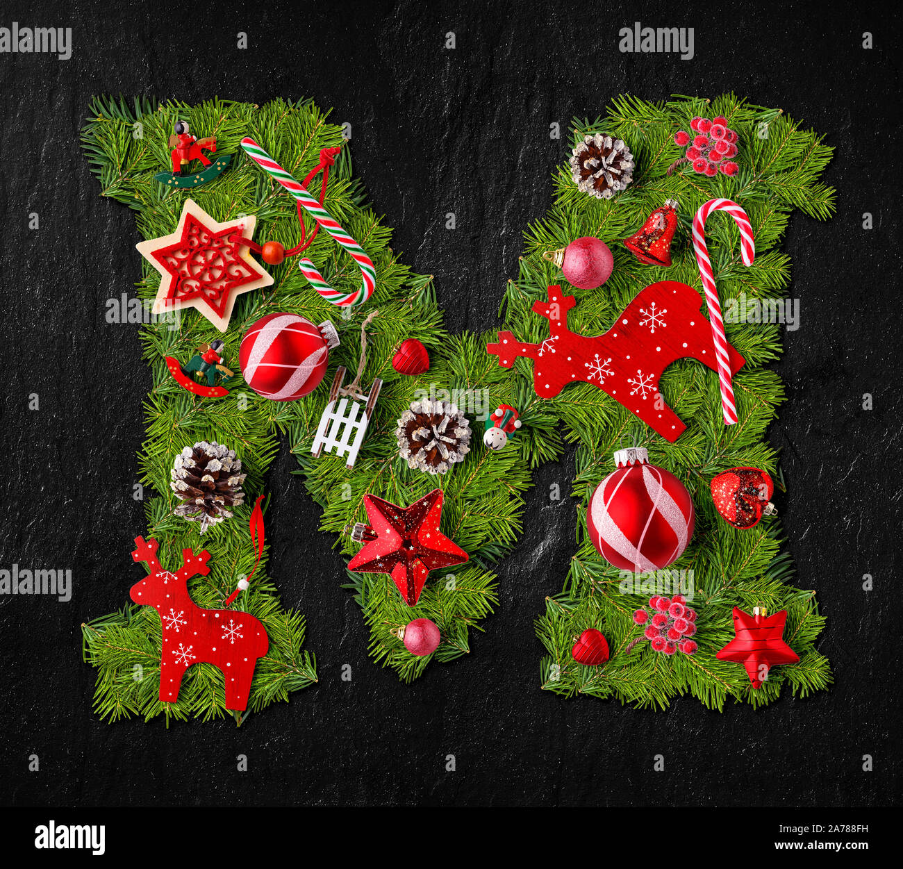 Letter M made of Christmas tree ornaments on a black slate background ...