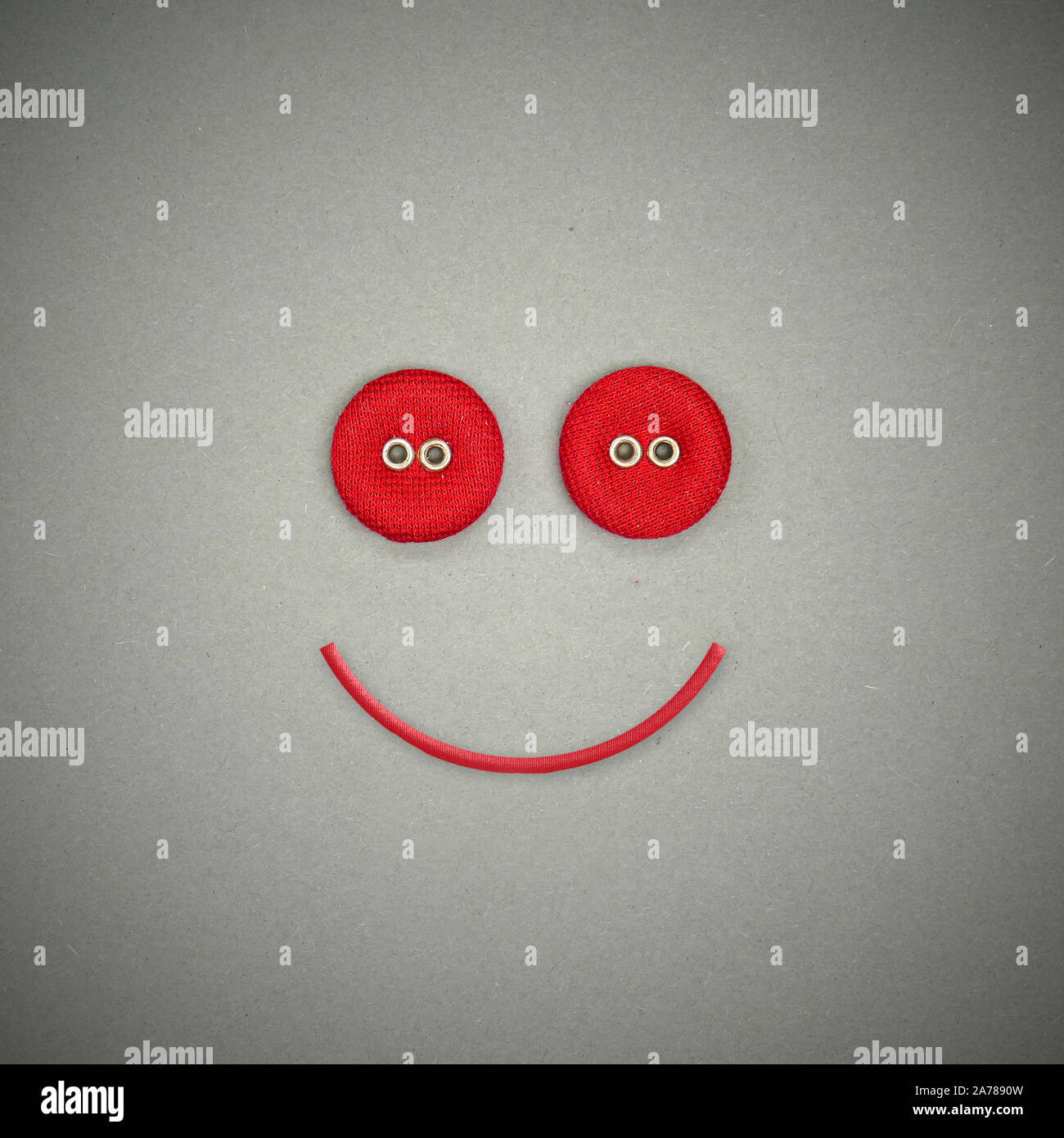 Smiling face made from red sewing buttons on gray background, minimal ...