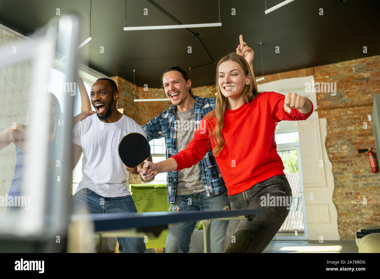 Young people playing table tennis in workplace, having fun. Friends in ...