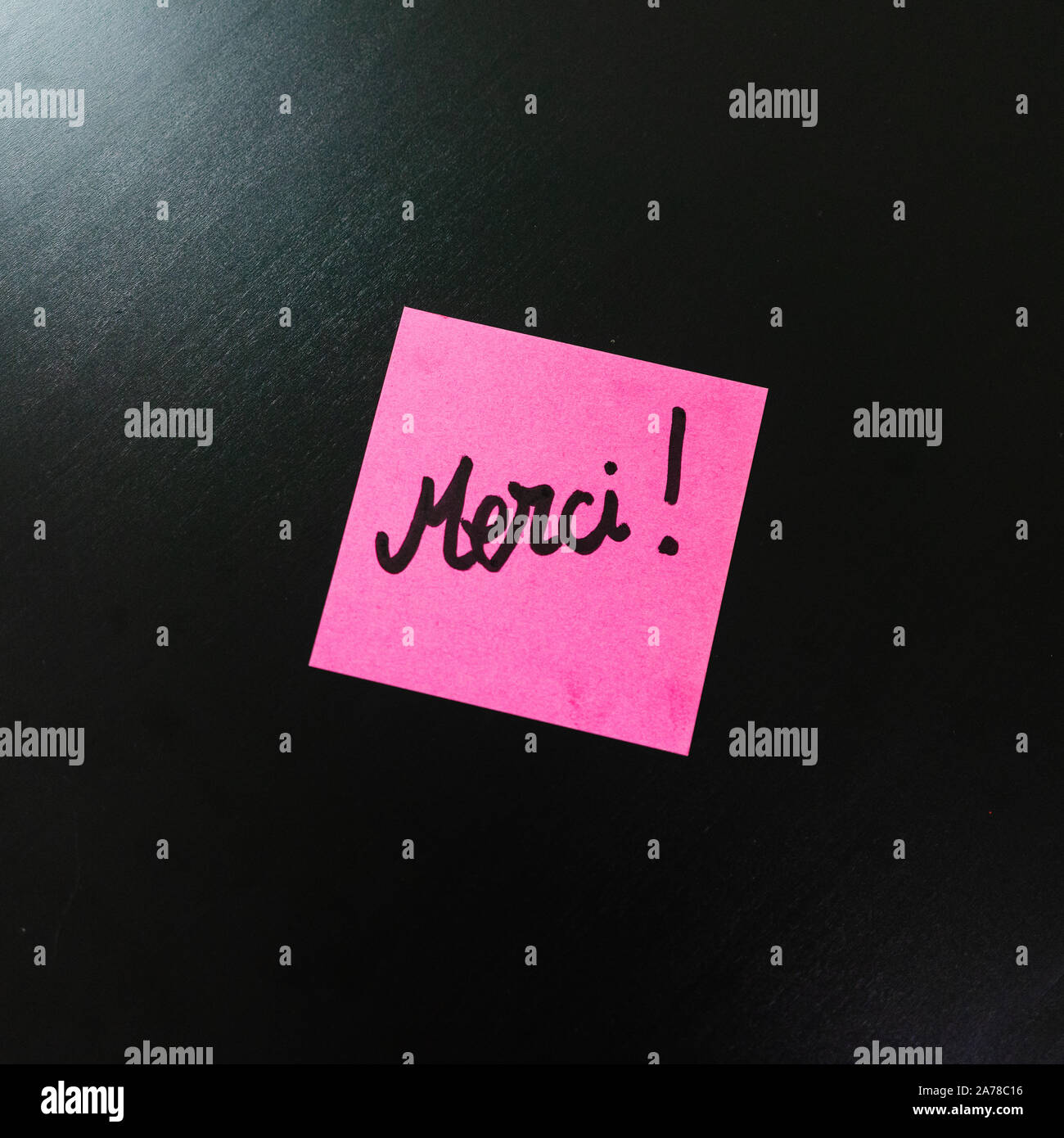 Text Merci on sticky note. Pink sticky note on black background Stock ...
