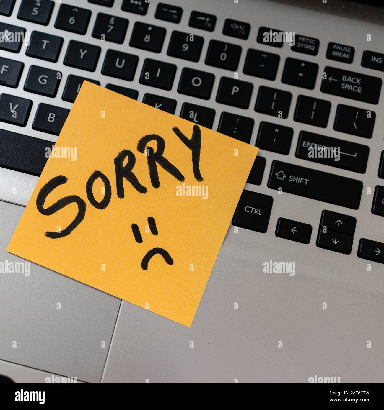 Text Sorry on sticky note. Orange note on keyboard Stock Photo - Alamy