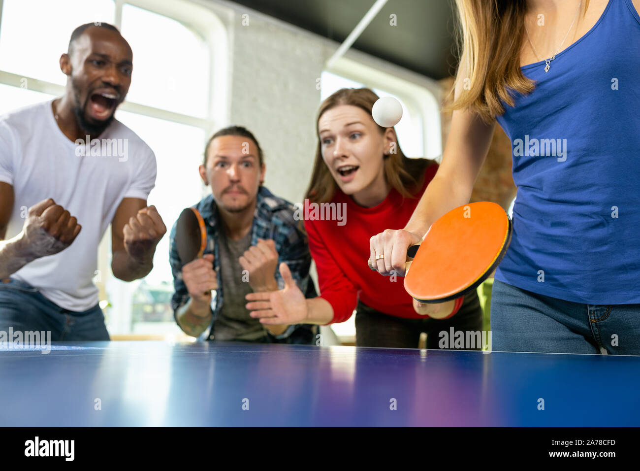 Young people playing table tennis in workplace, having fun. Friends in ...