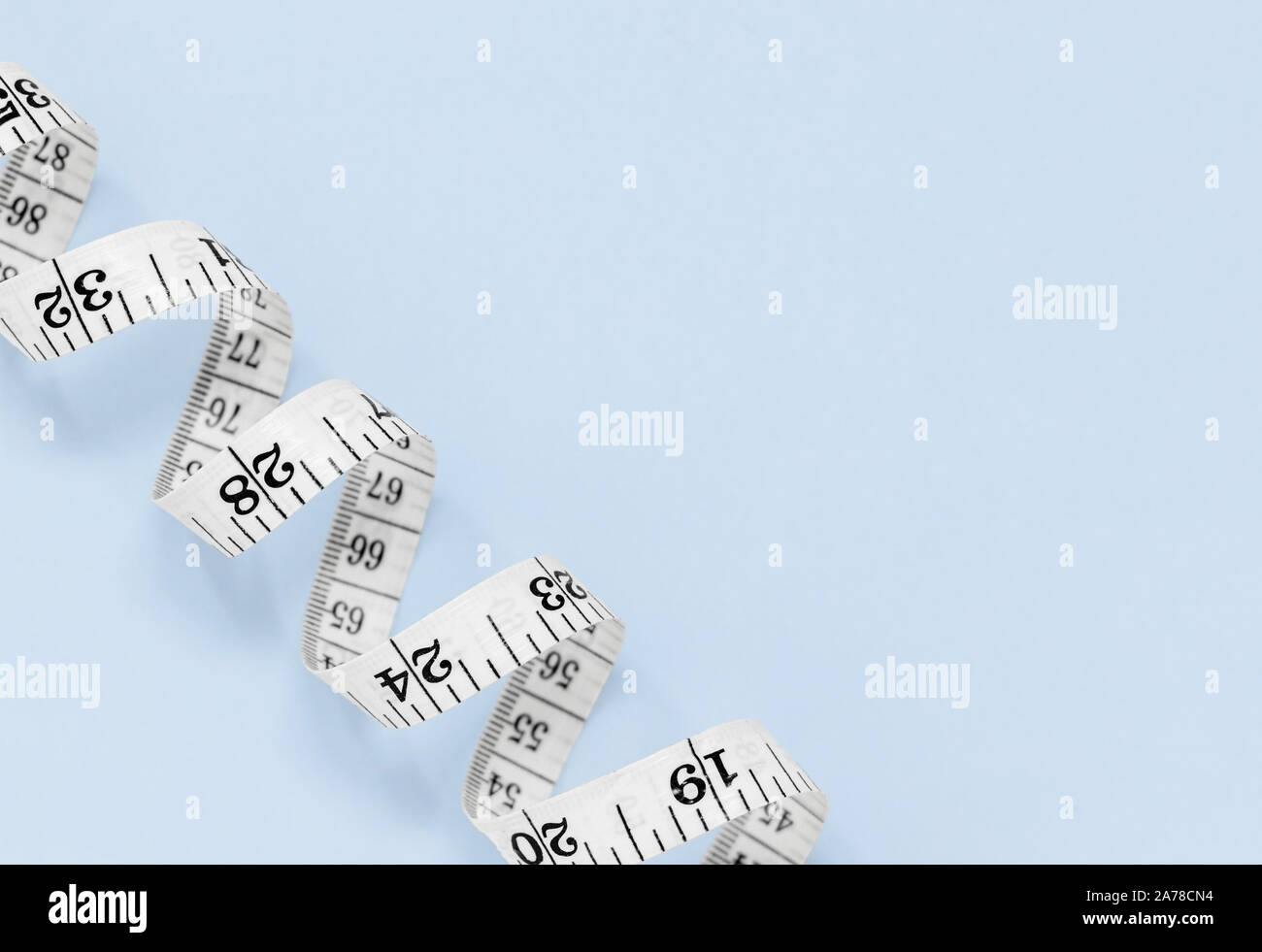 White measuring tape isolated on a blue background, with copy space ...