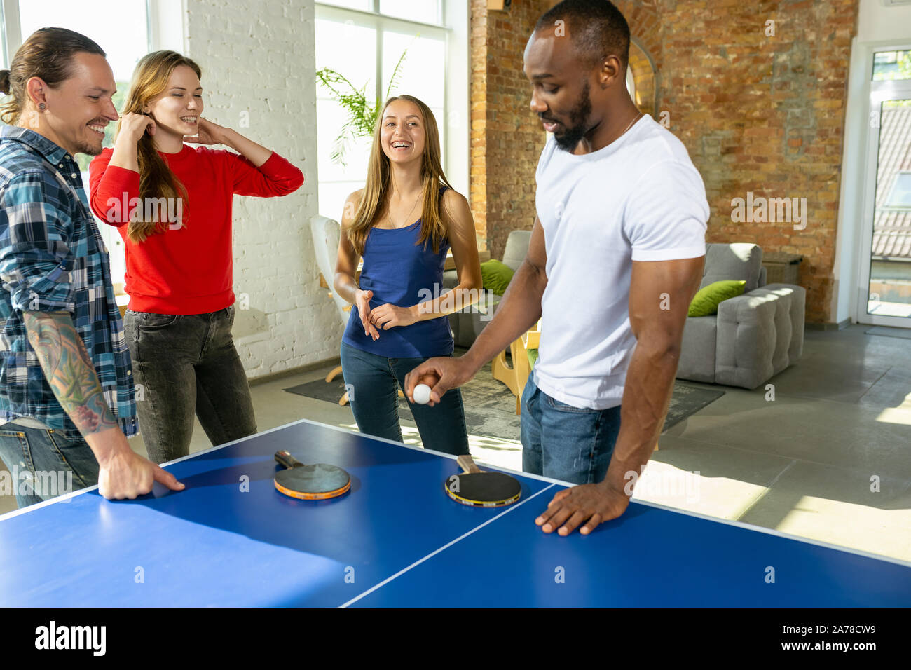 Young people playing table tennis in workplace, having fun. Friends in ...