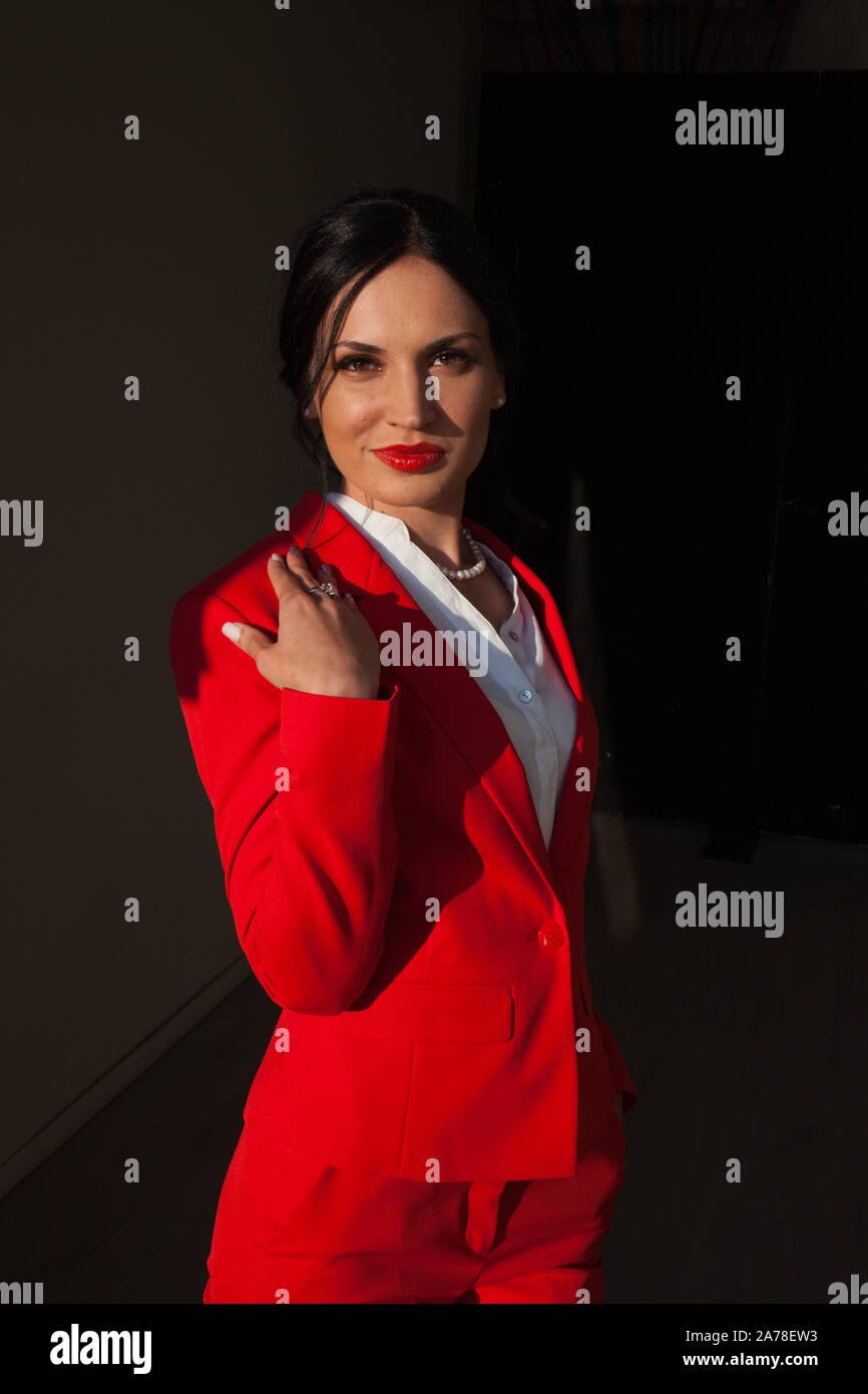Portrait of a beautiful business woman in a red business suit in the ...