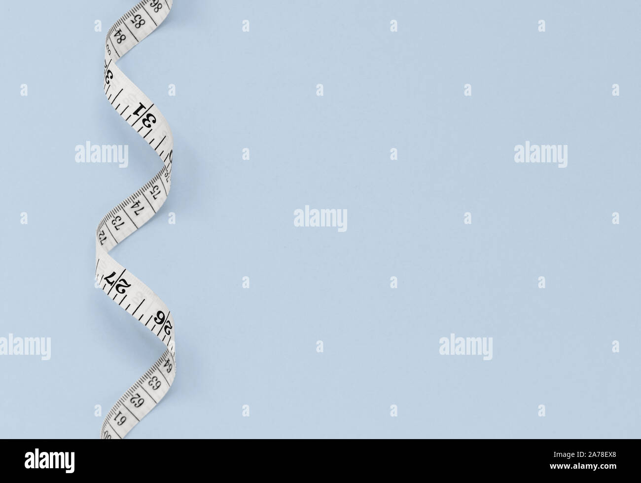 White measuring tape isolated on a blue background, with copy space ...