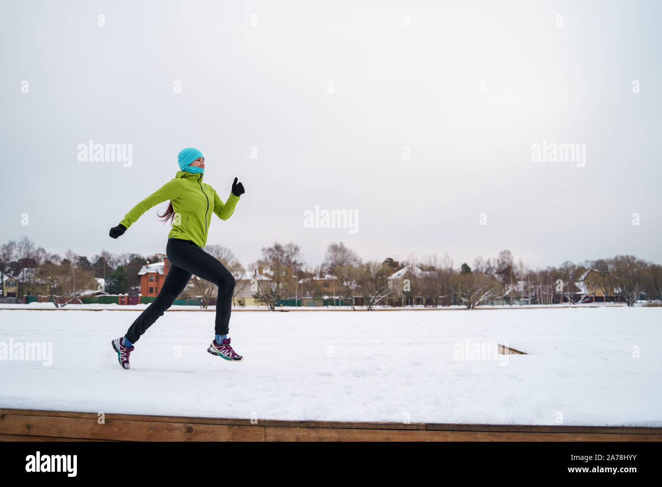 Picture of young athlete woman running at winter park in afternoon ...