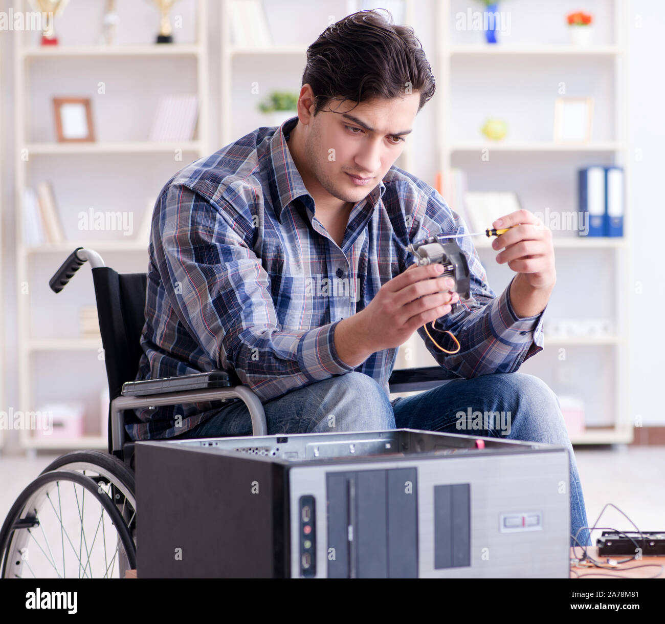 The disabled man on wheelchair repairing computer Stock Photo - Alamy