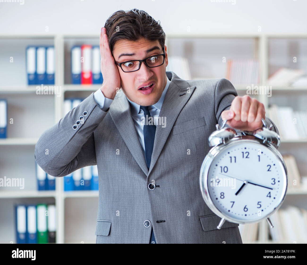 The businessman with alarm clock in the office Stock Photo - Alamy