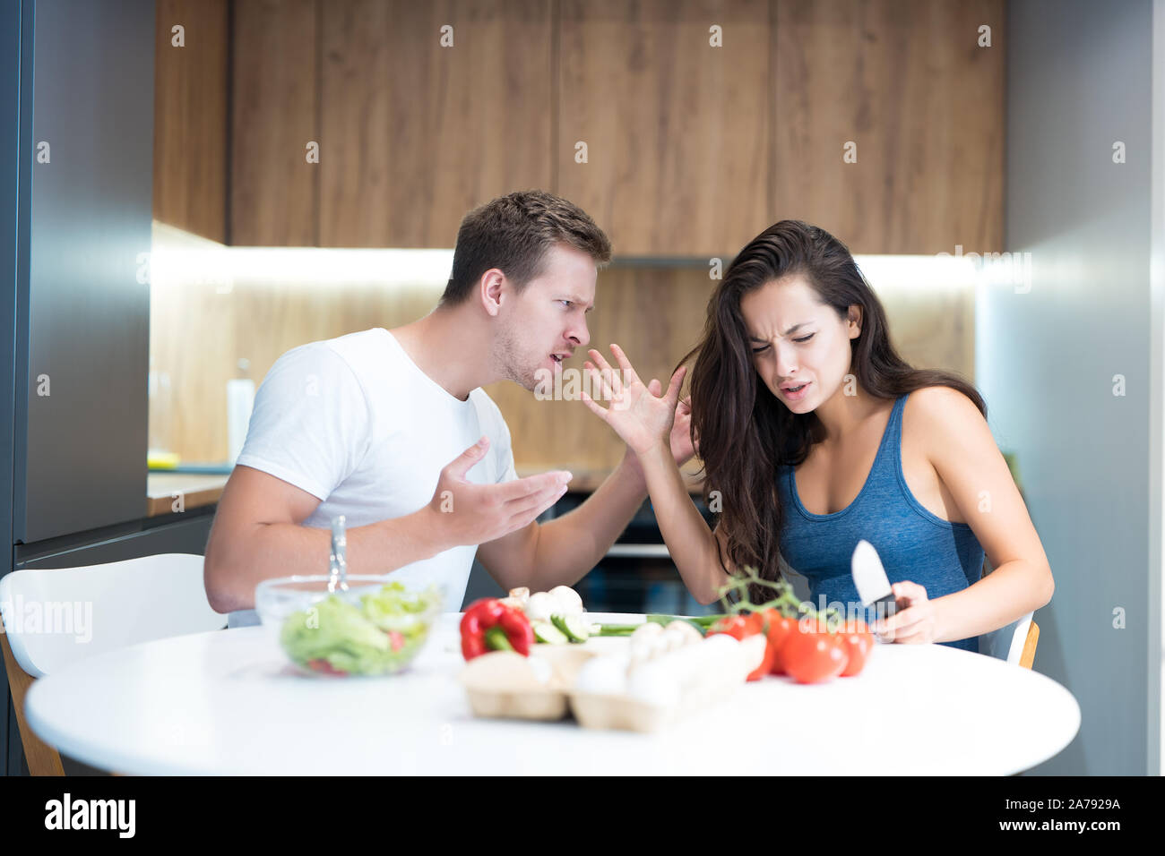 young couple having fight while cooking breakfast in the kitchen ...