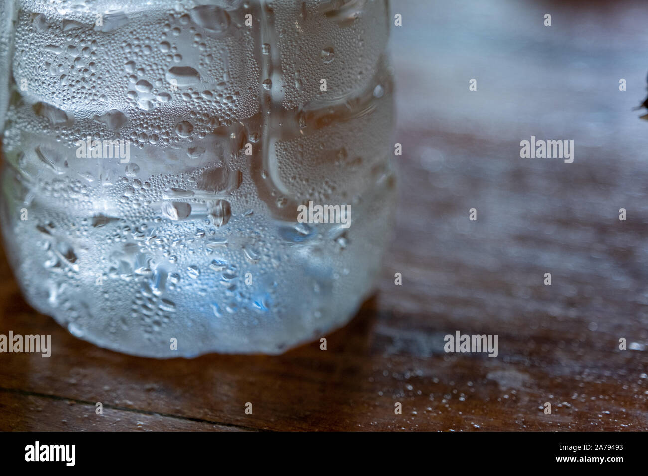 Clear water drop on cool water bottle on wooden table with blur ...