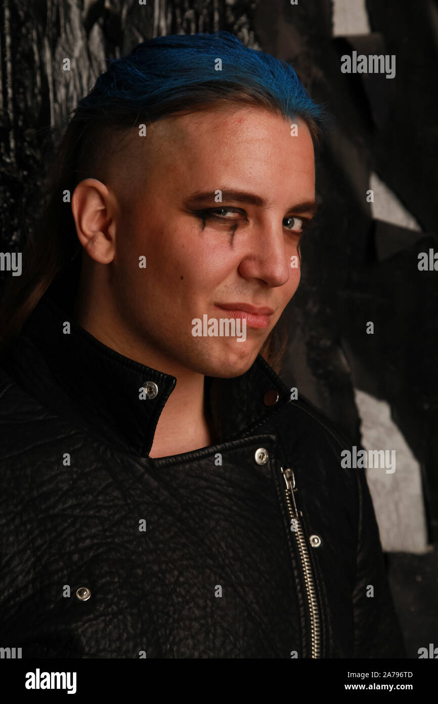 Teen alt boy with blue hair and shaved head dressed in black on dark ...