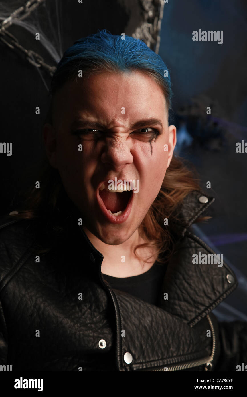 Teen alt boy with blue hair and shaved head dressed in black on dark ...