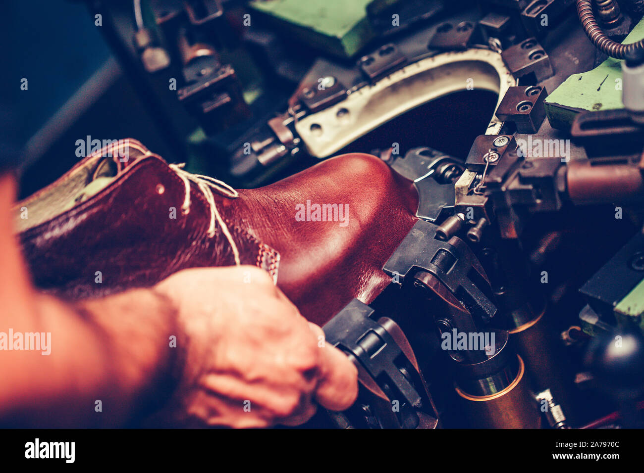 Experienced shoemaker using a special machine for putting shoes on the ...