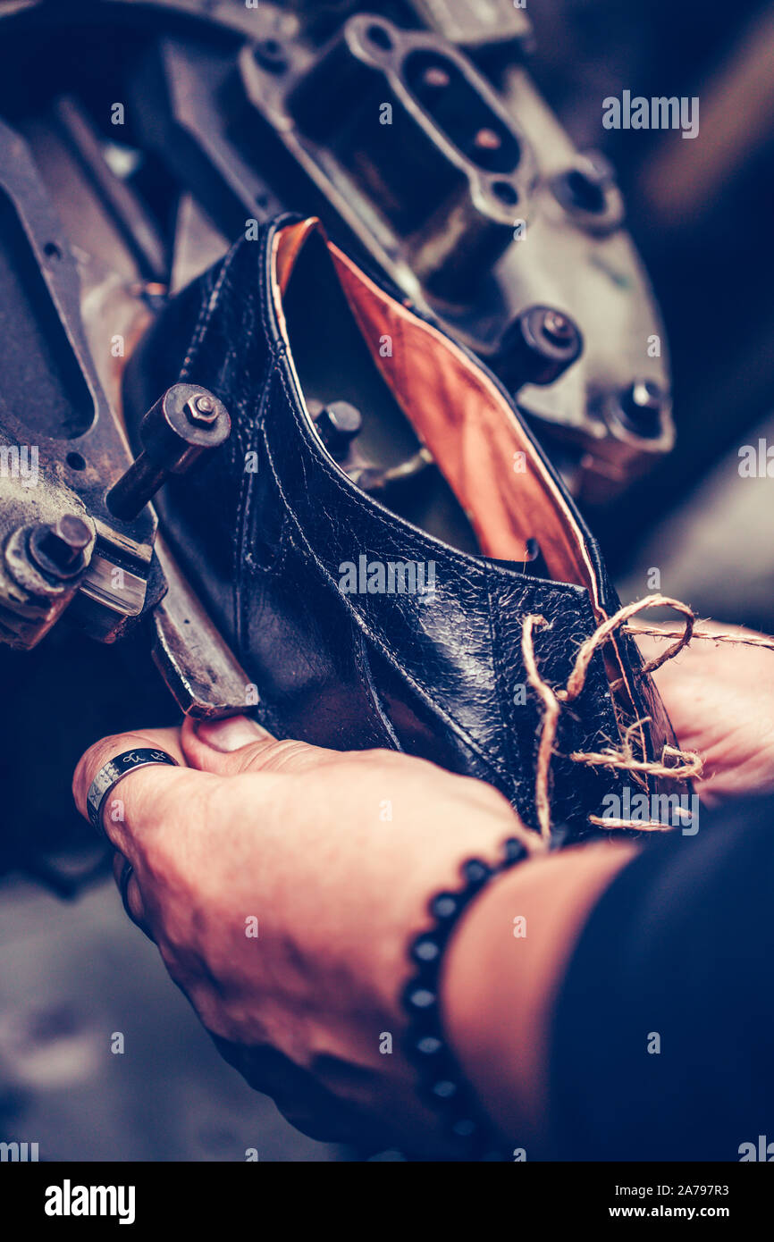 Hands of an experienced shoemaker using special machine tool for making ...
