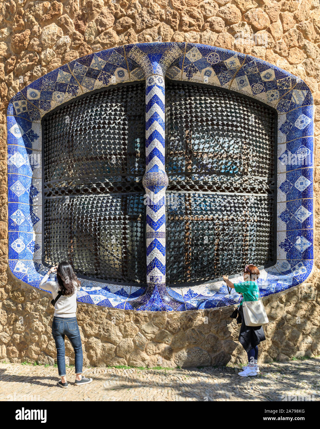 Tourists photograph mosaic tiling on a building by Antoni Gaudi at the ...