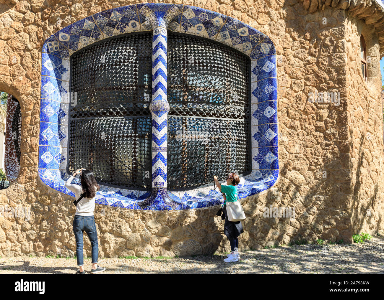 Tourists photograph mosaic tiling on a building by Antoni Gaudi at the ...