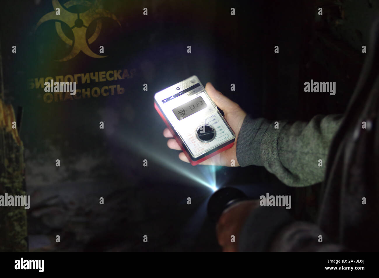 A man with a biohazard meter and a flashlight before a warning about ...