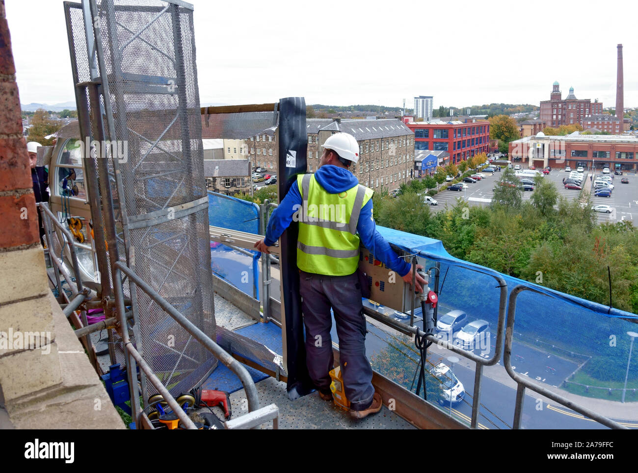 Workman operating a mast climber at height in Paisley, Scotland Stock ...
