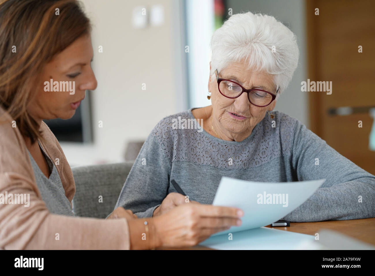 Home assistant helping elderly woman with paper work Stock Photo - Alamy