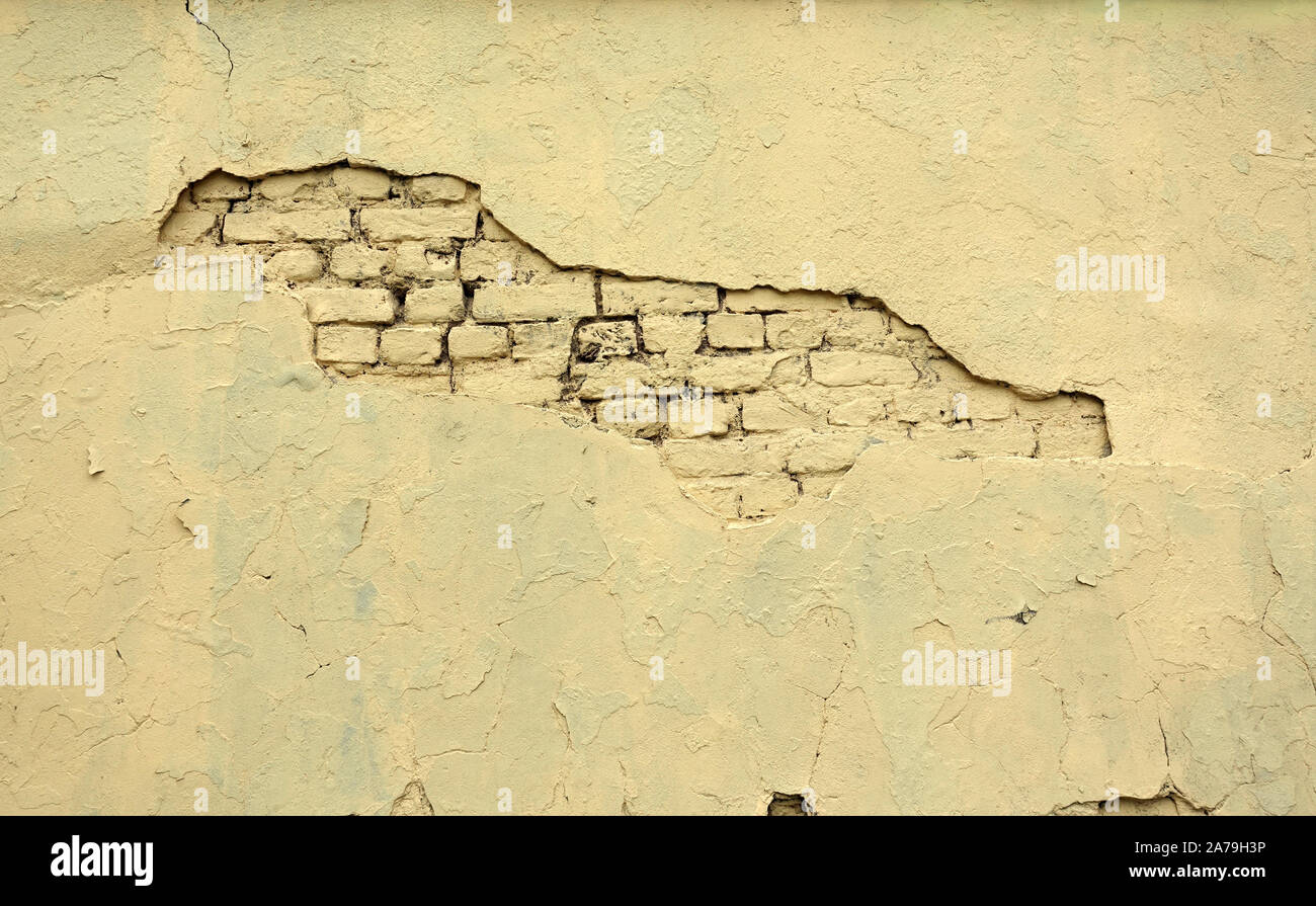 Retro brick wall painted yellow color coated with plaster damaged in ...