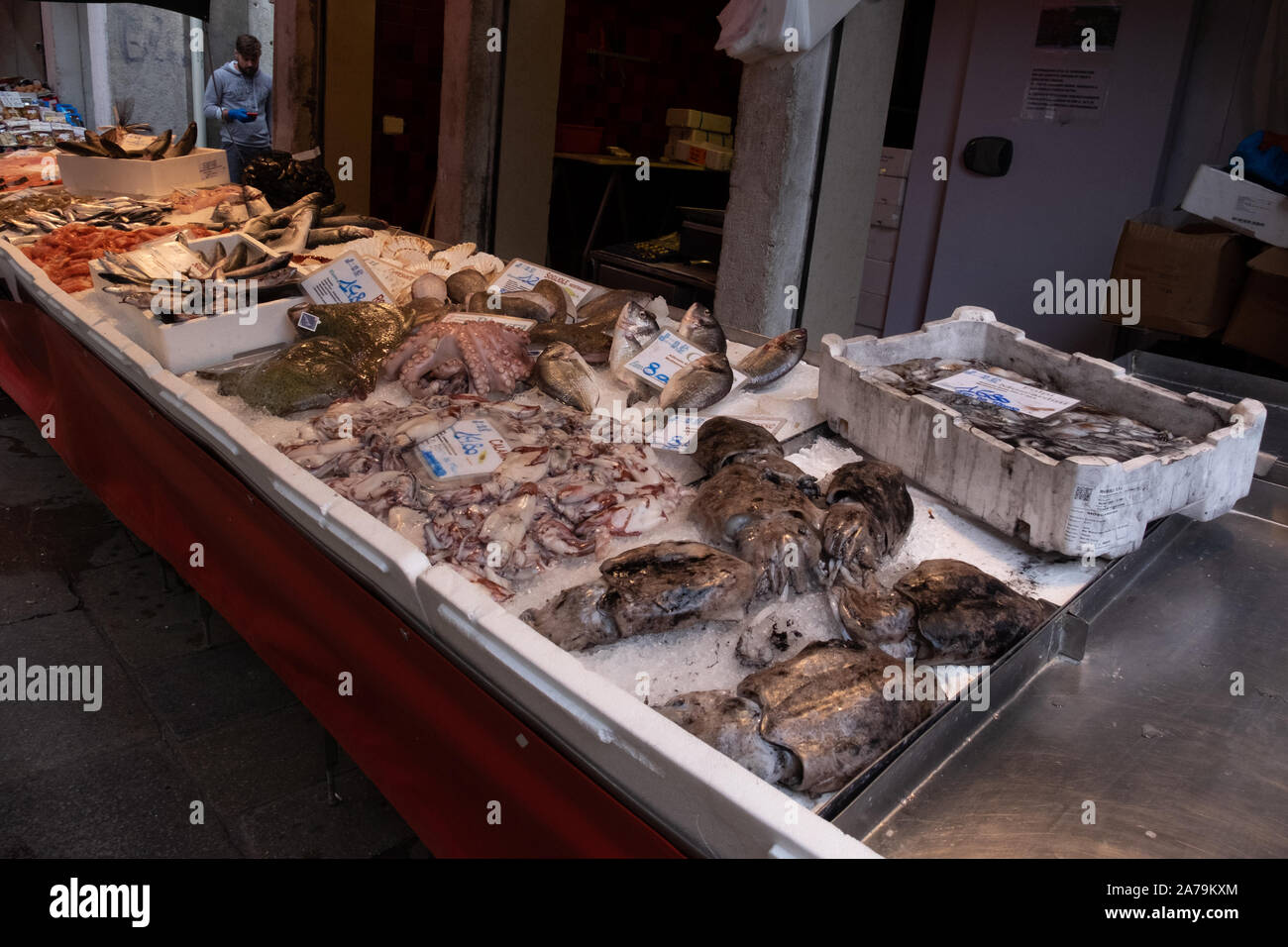 Fishmonger selling from an amazing long bench of fish displays under a ...