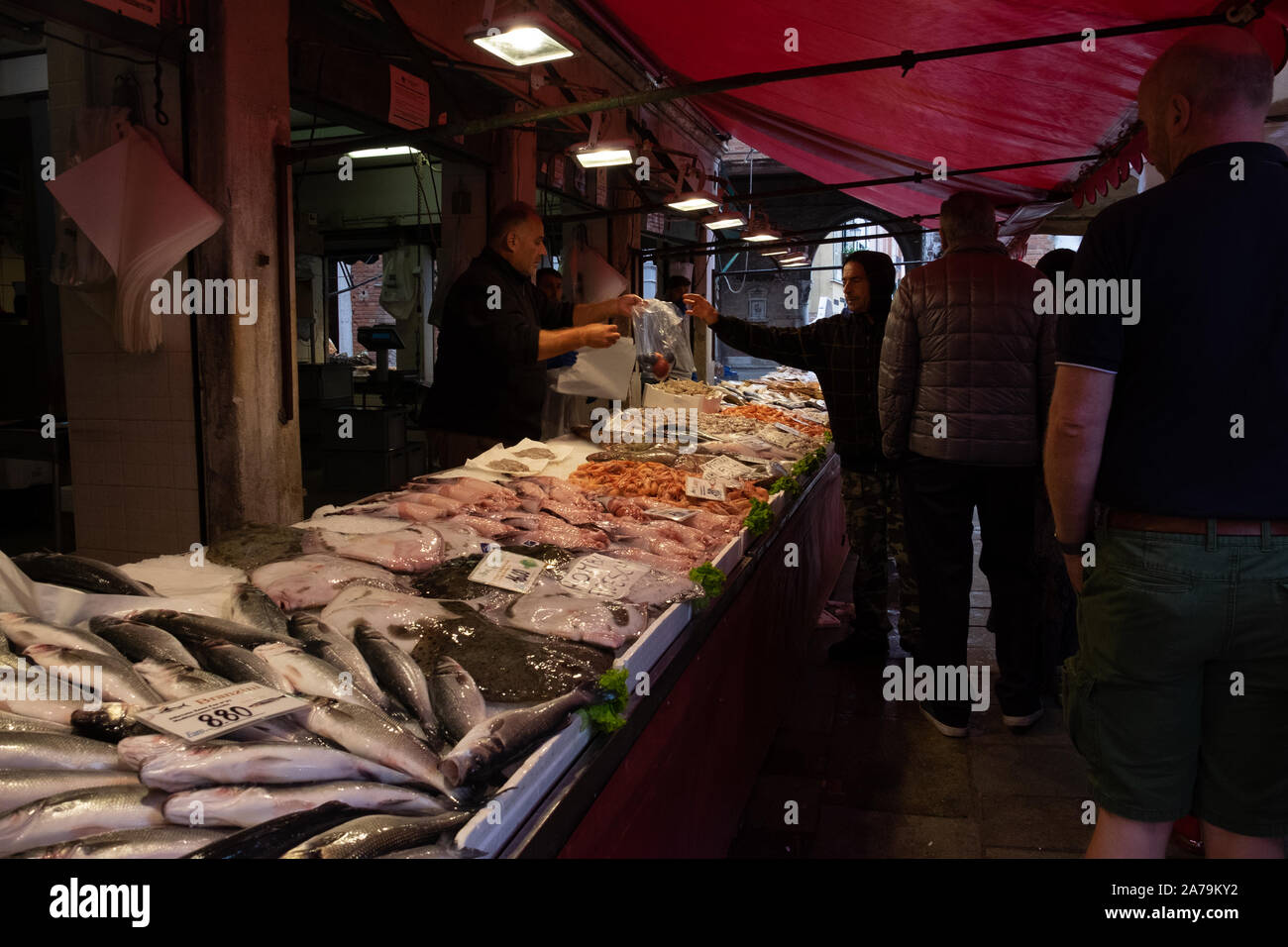 Fishmonger selling from an amazing long bench of fish displays under a ...