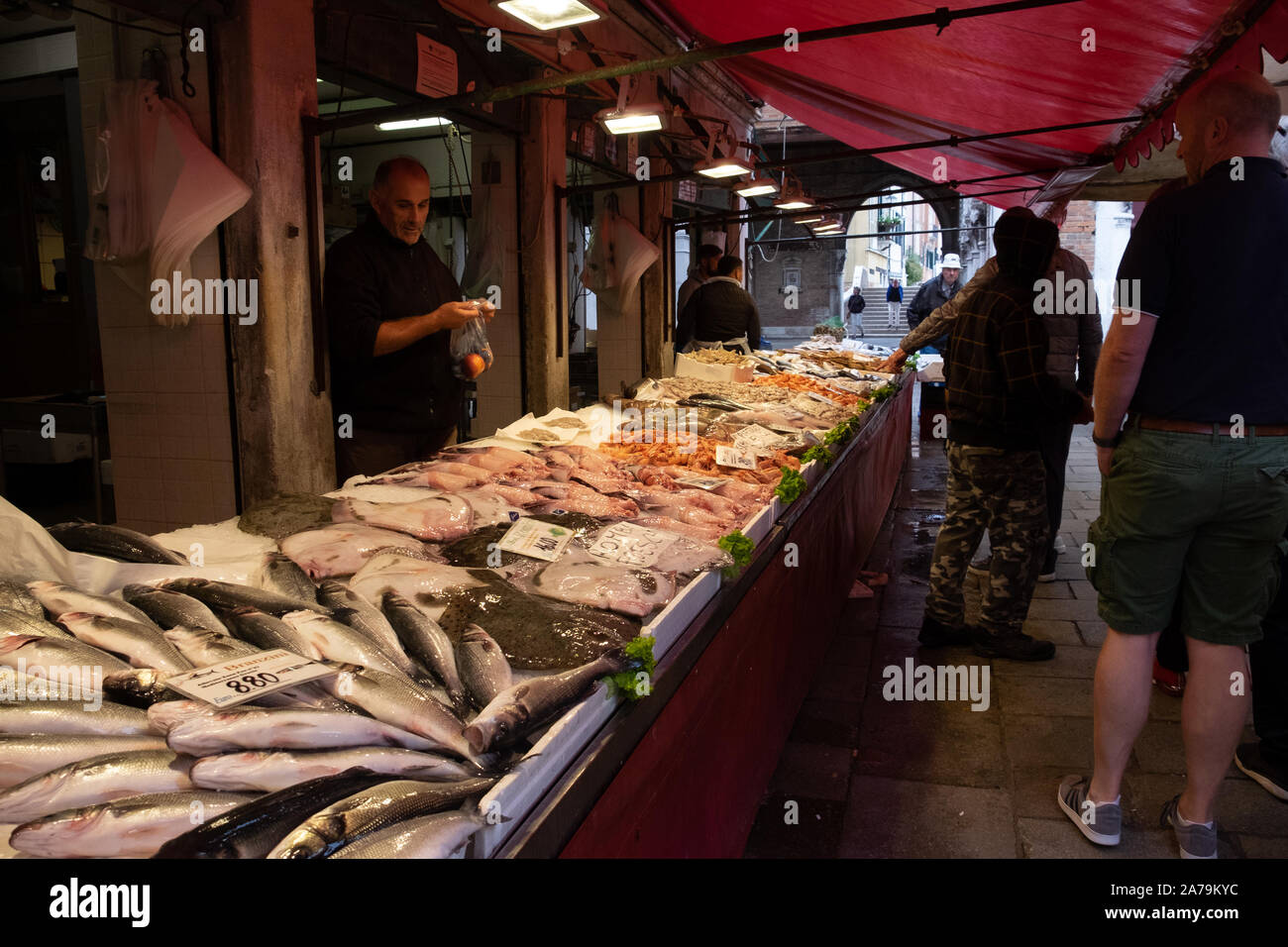 Fishmonger selling from an amazing long bench of fish displays under a ...