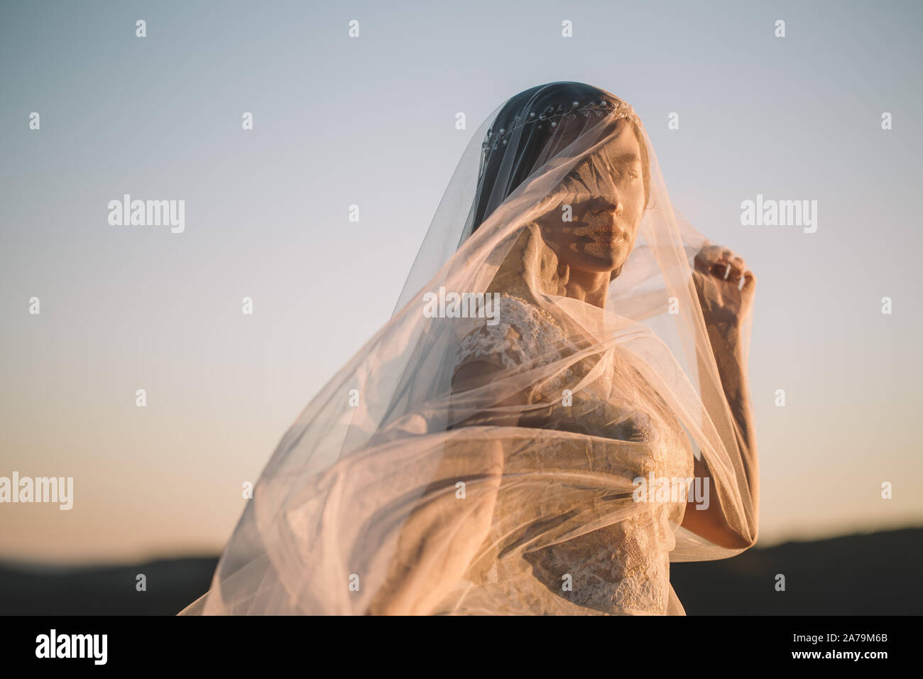 Beautiful young woman bride covered her face with a veil Curling in the ...
