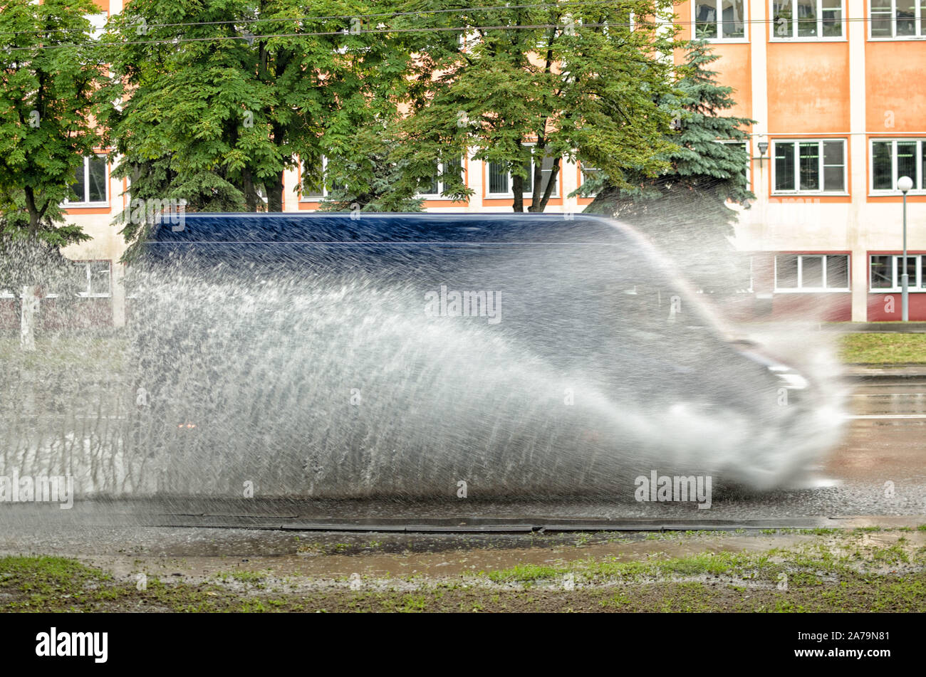 Cars move on asphalt through a huge puddle.Splashes from puddles ...
