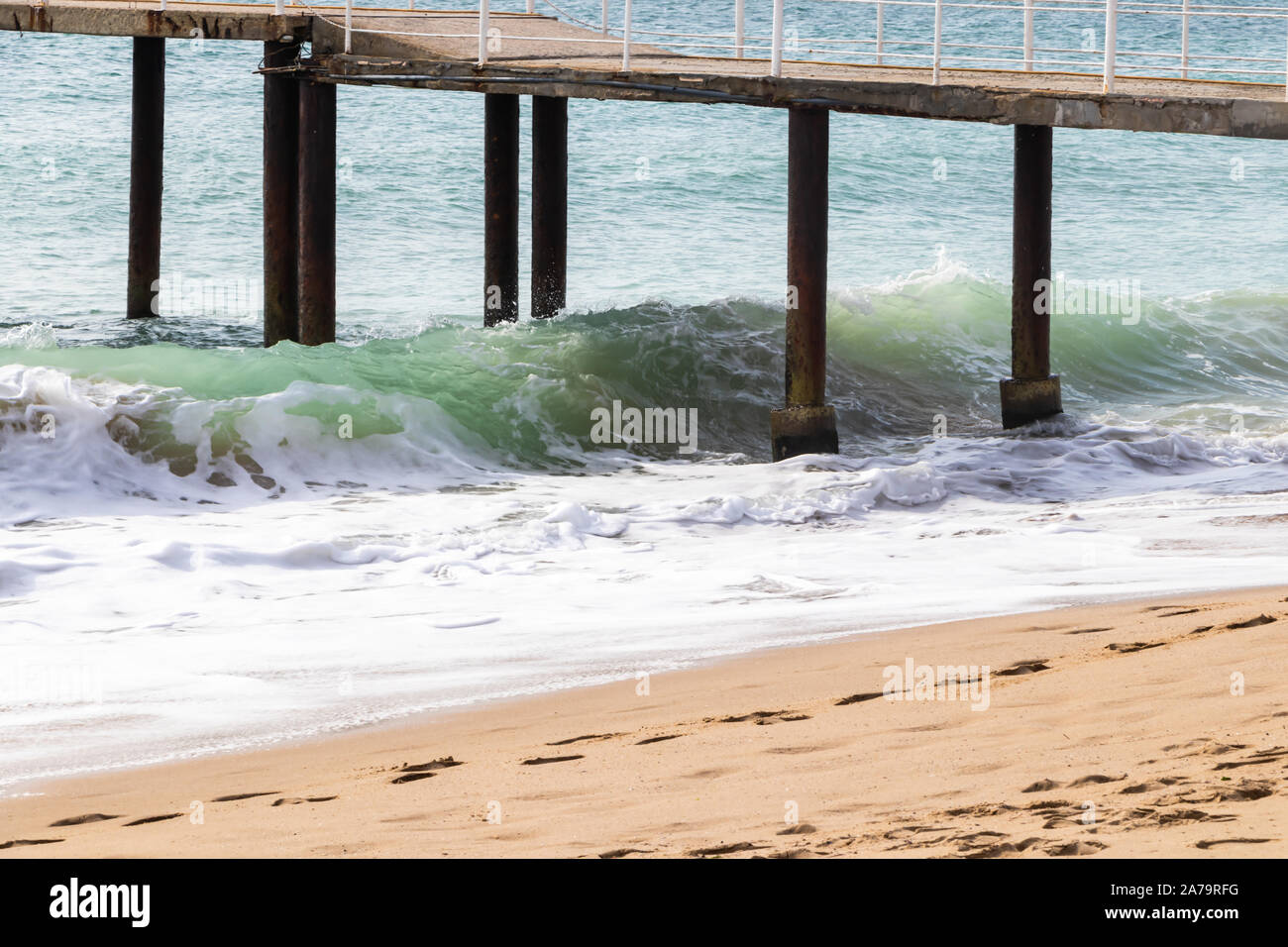 Waves under jetty at the beach Stock Photo - Alamy