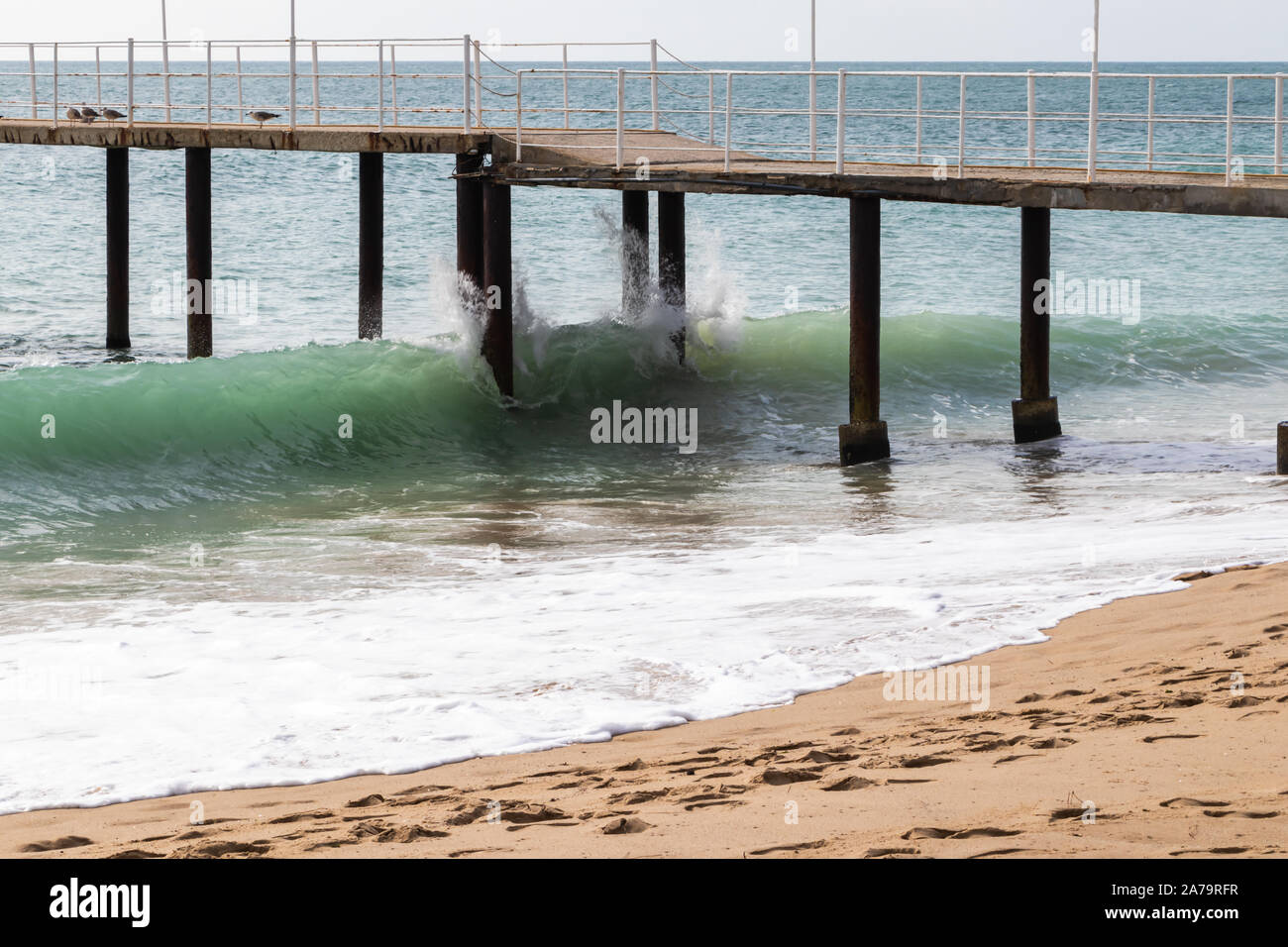 Waves under jetty at the beach Stock Photo - Alamy