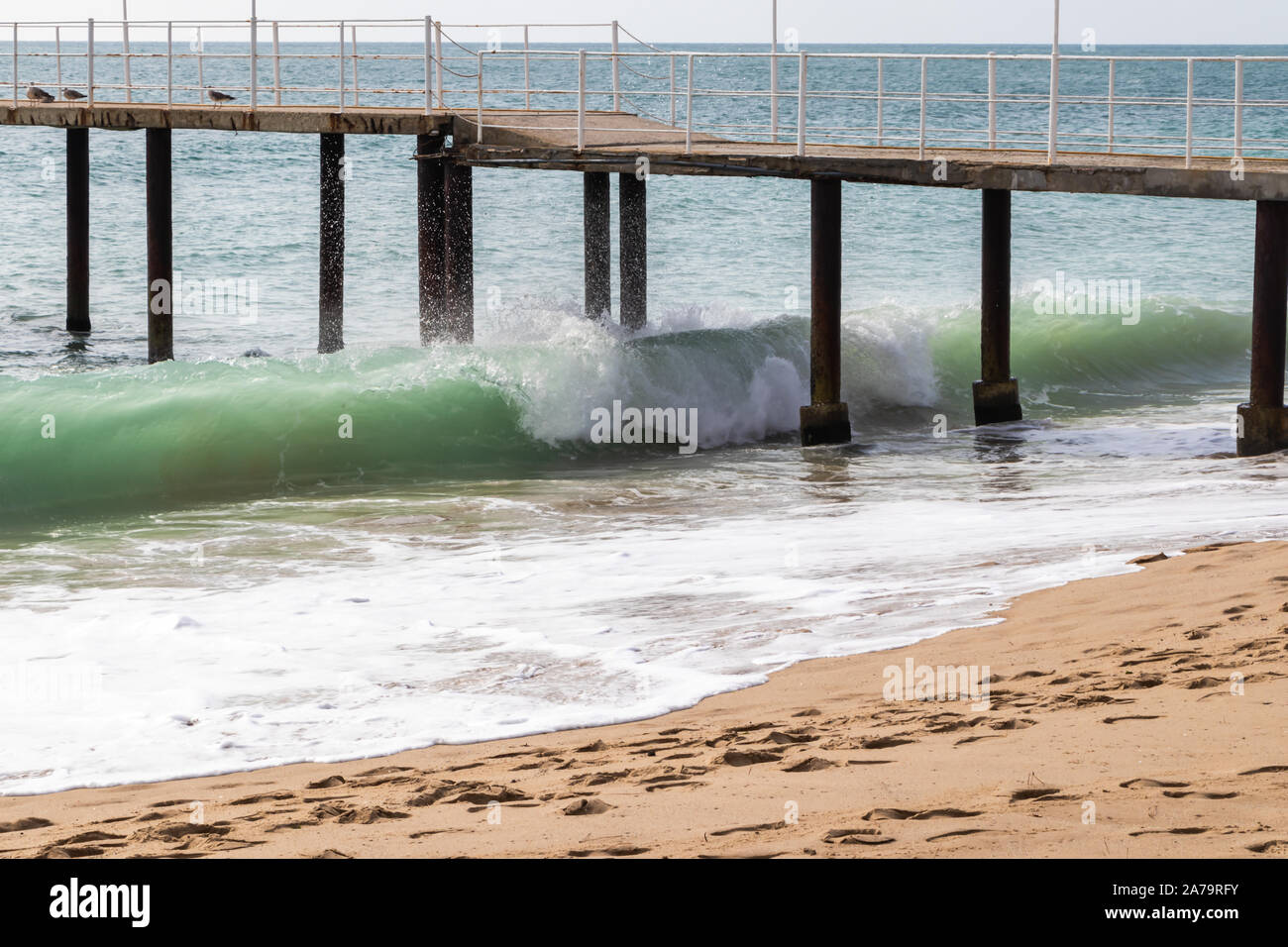 Waves under jetty at the beach Stock Photo - Alamy