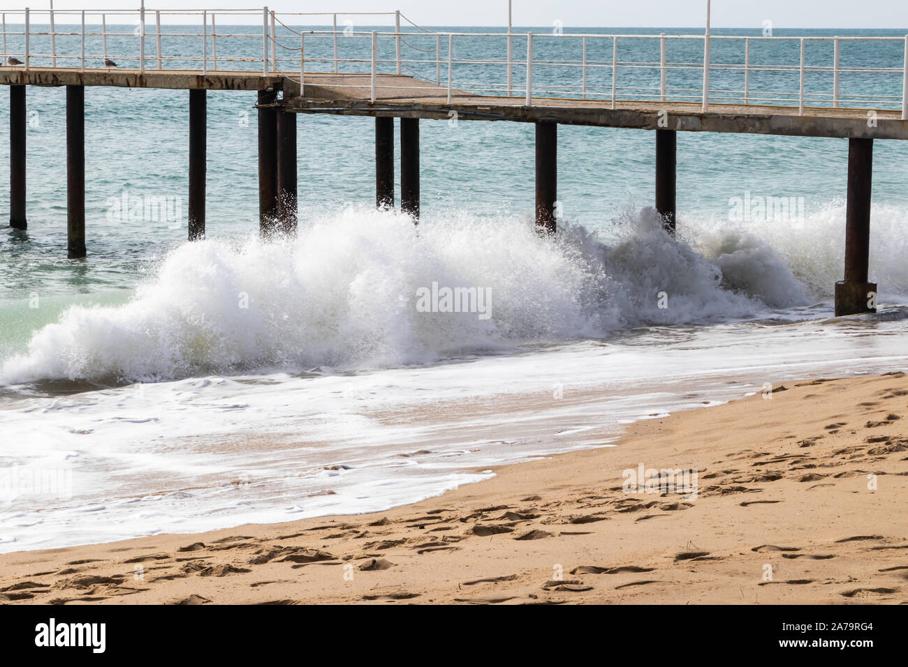 Waves under jetty at the beach Stock Photo - Alamy