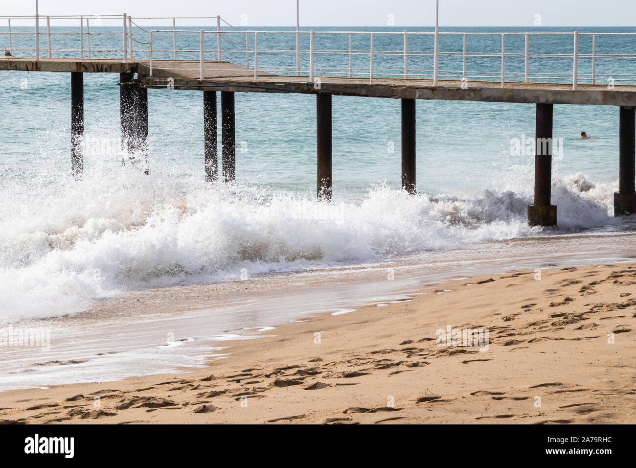 Waves under jetty at the beach Stock Photo - Alamy