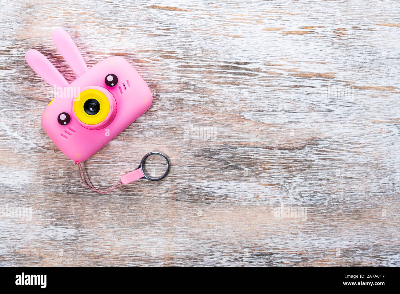 Pink camera with funny ears and a mug on a light wooden background ...
