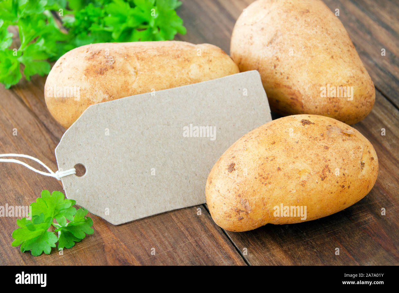 Potatoes on wooden background with label Stock Photo - Alamy