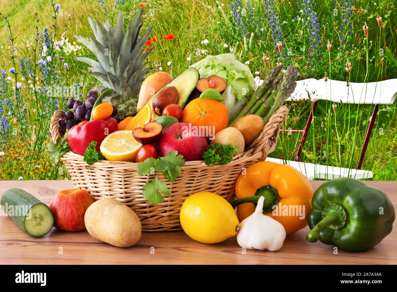 Spring meadow with colorful flowers and fruit and vegetables in basket ...