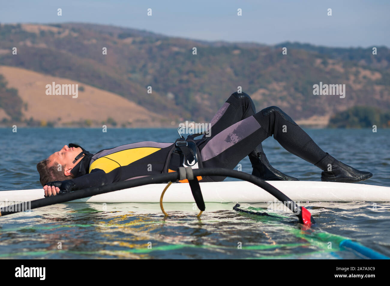 Young windsurfer resting on surfboard in ocean. Sport and recreation ...