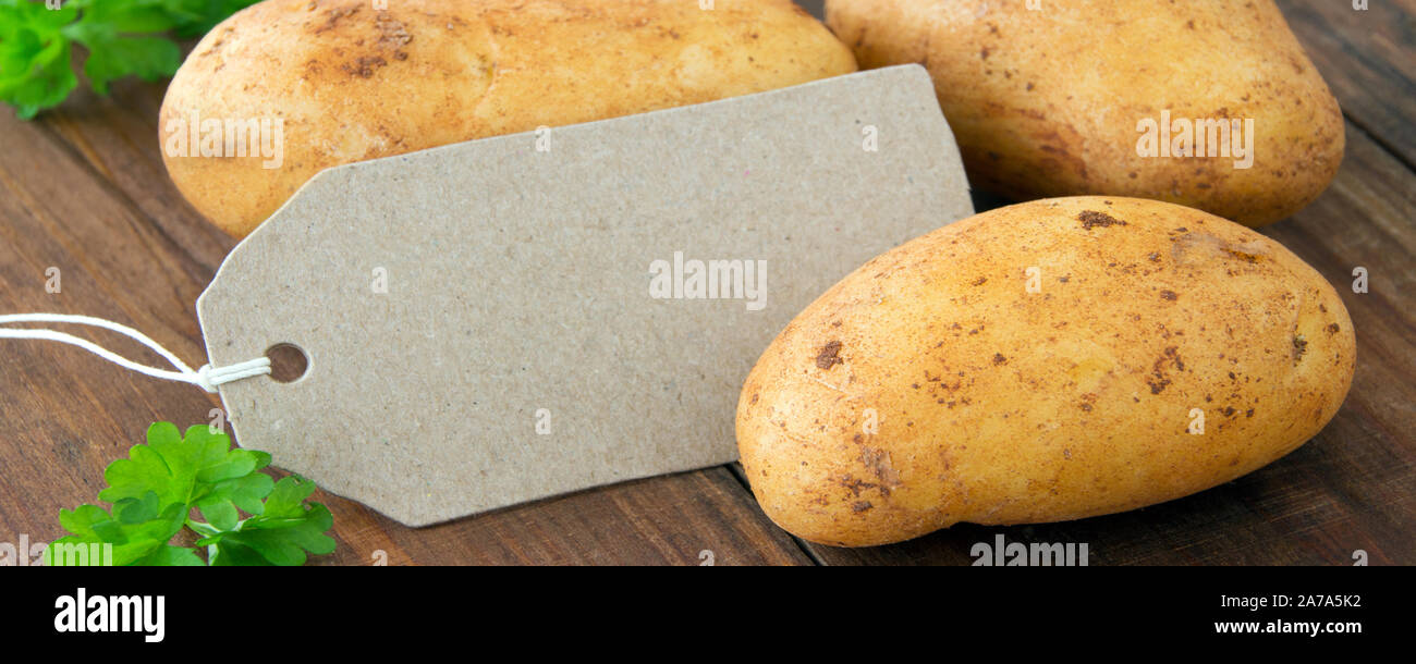 Potatoes on wooden background with label Stock Photo - Alamy