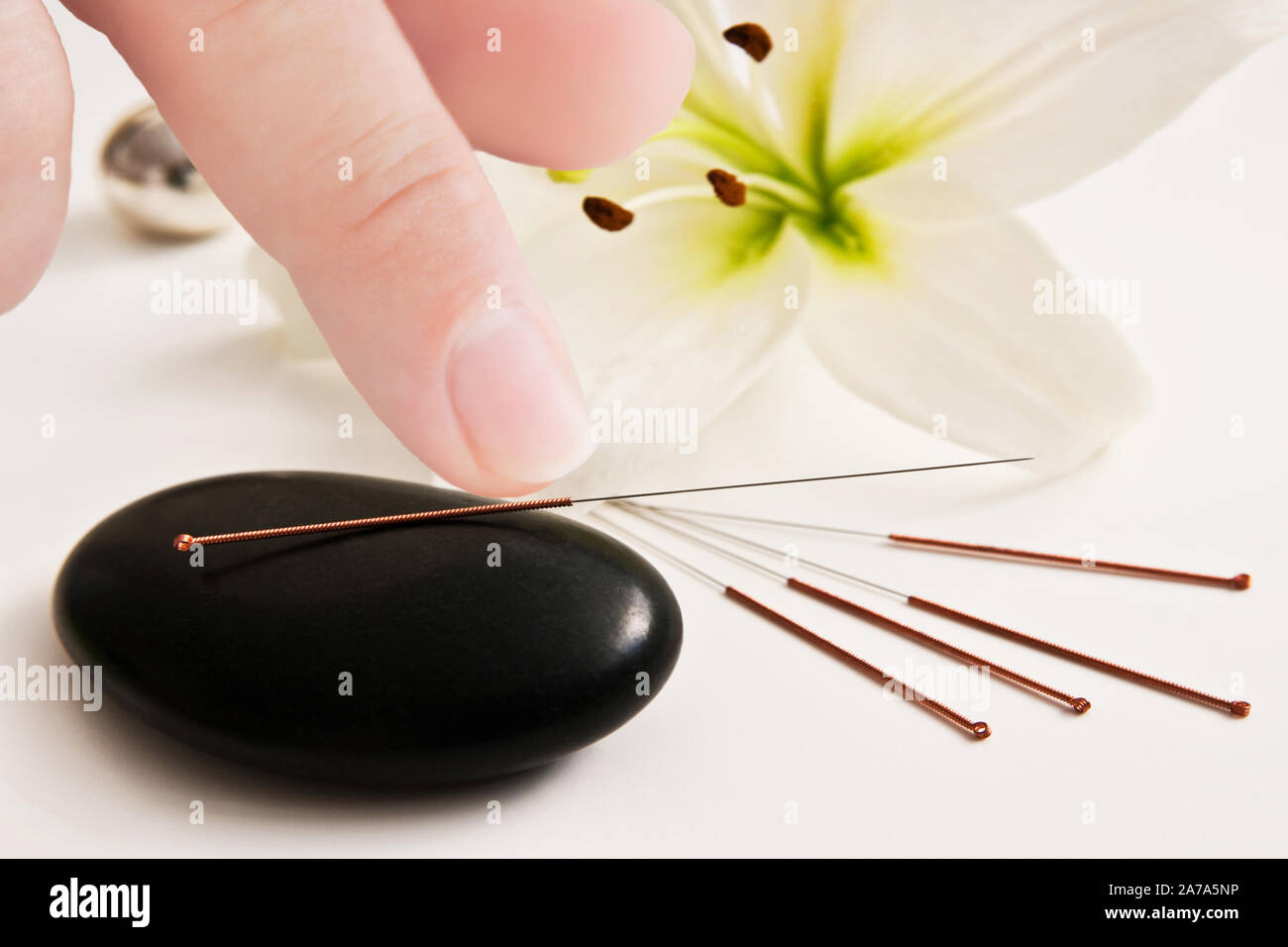 Acupuncture needles with lily and stones background Stock Photo - Alamy