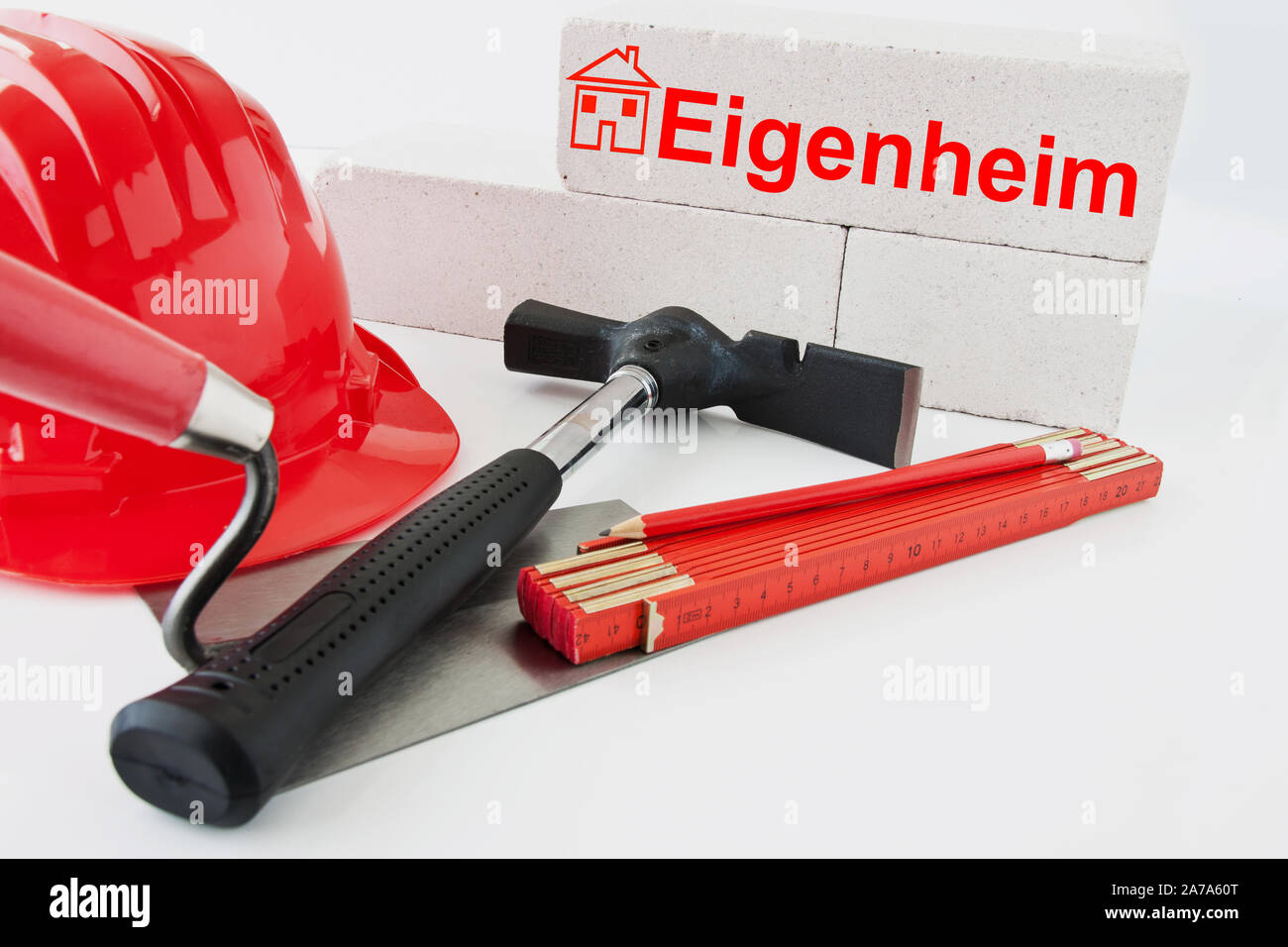 Construction helmet, folding rule, hammer and bricks on white ...