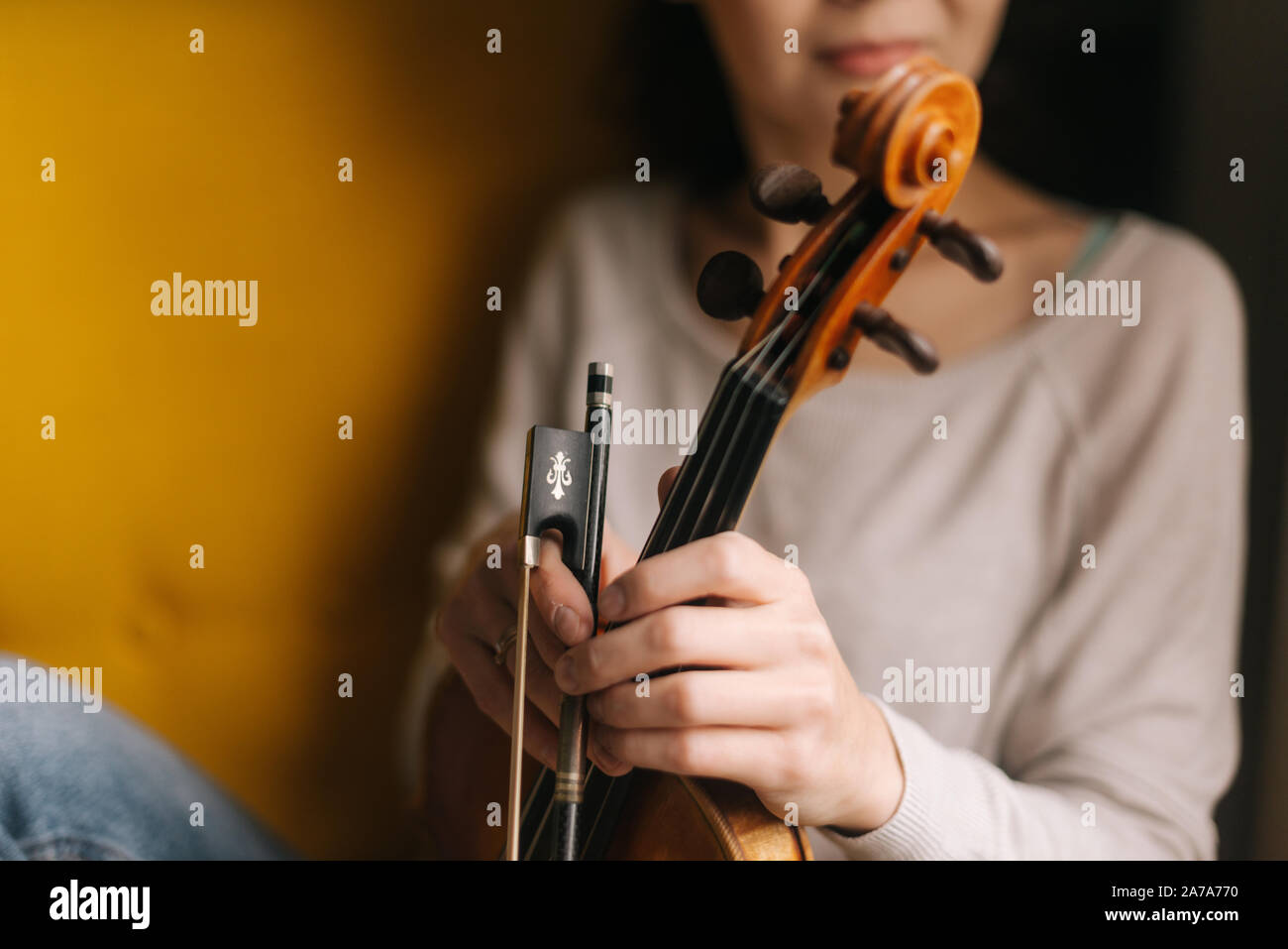 Beautiful girl posing with a violin in a soft chair Stock Photo - Alamy