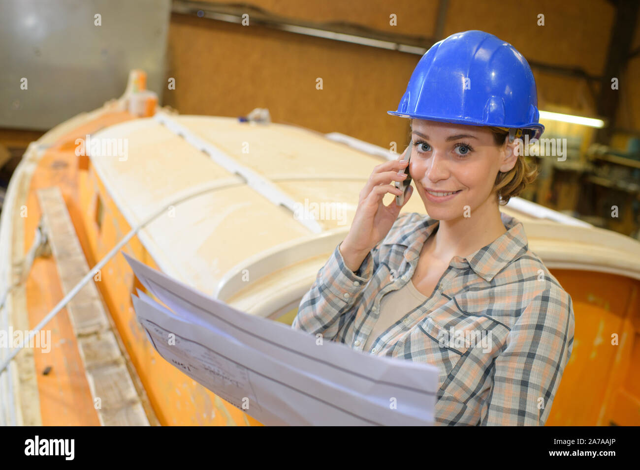 boat mechanic smiling while using the phone at garage Stock Photo - Alamy
