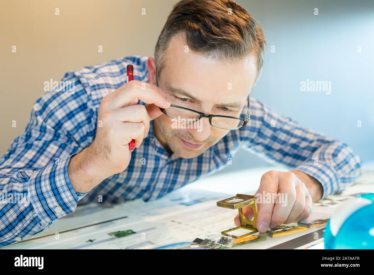 worker in a printing uses a magnifying glass Stock Photo - Alamy