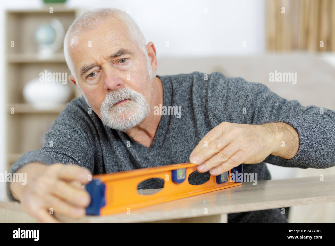 senior man with working with a spirit level Stock Photo - Alamy