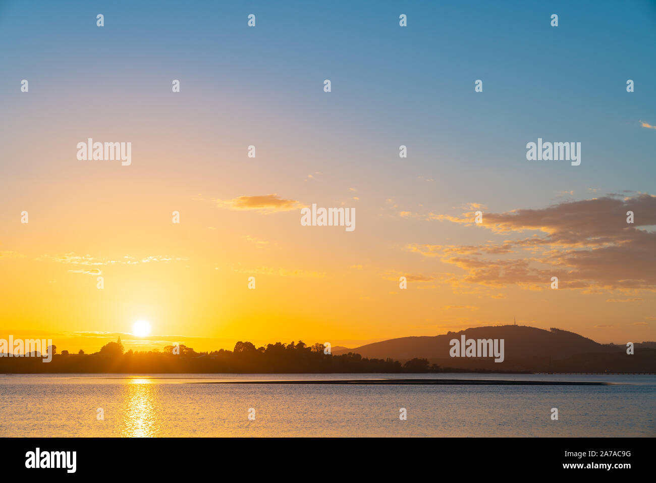 Clear summer sunrise over low silhouette horizon with cloud catching ...