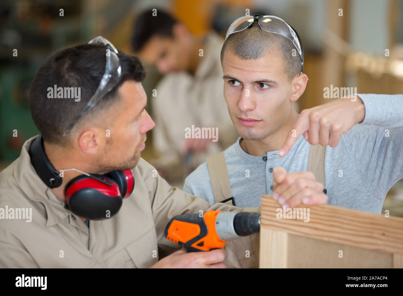 two men measuring detail and assembling product in carpentry workshop ...